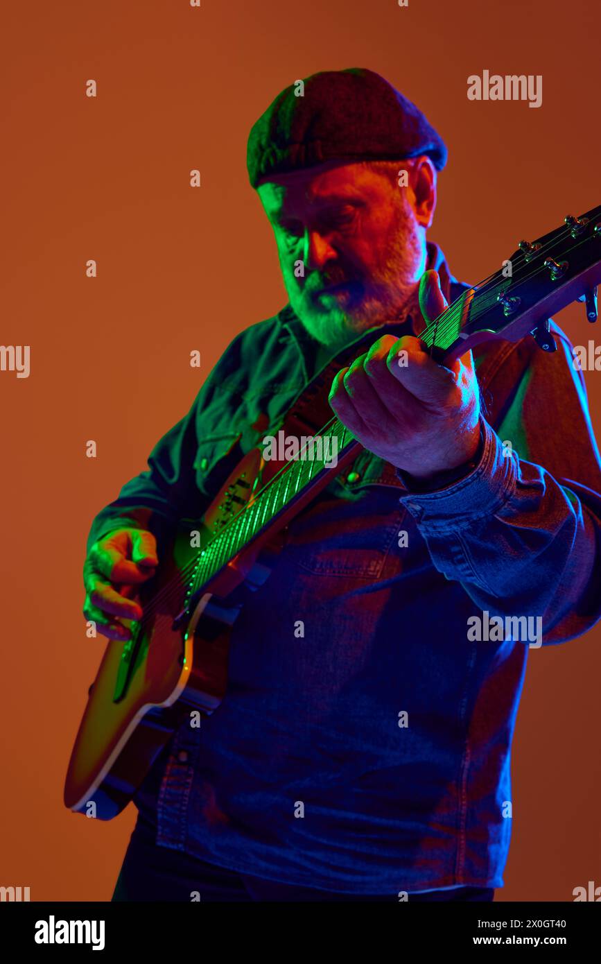 Guitarist with beard intently adjusts electric guitar in colorful neon ...