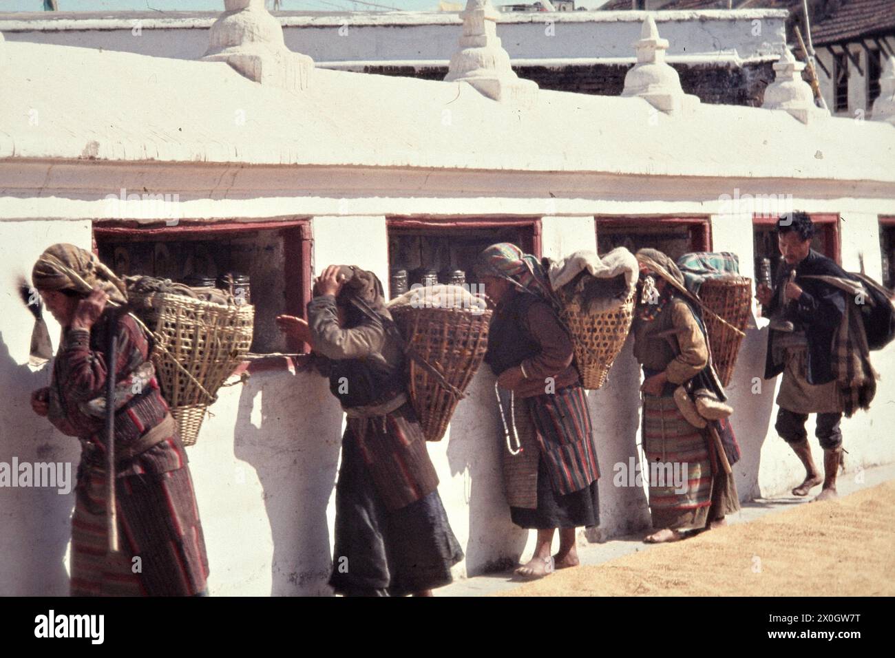 Tibetan pilgrimage group at the prayer wheels at the foot of the ...