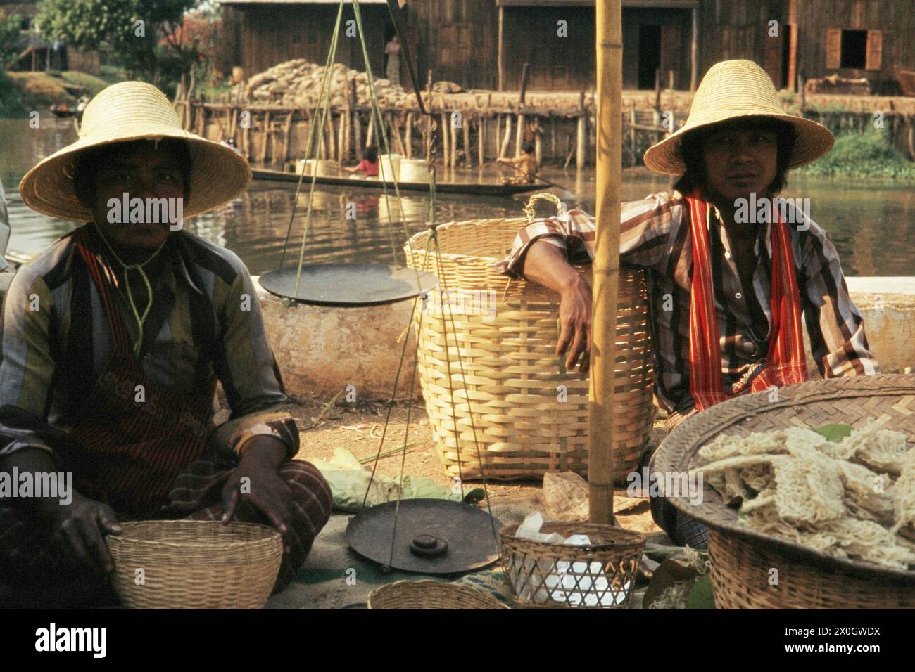 Two sellers at the Hpaung Daw U Pagoda with baskets and a scale on the ...
