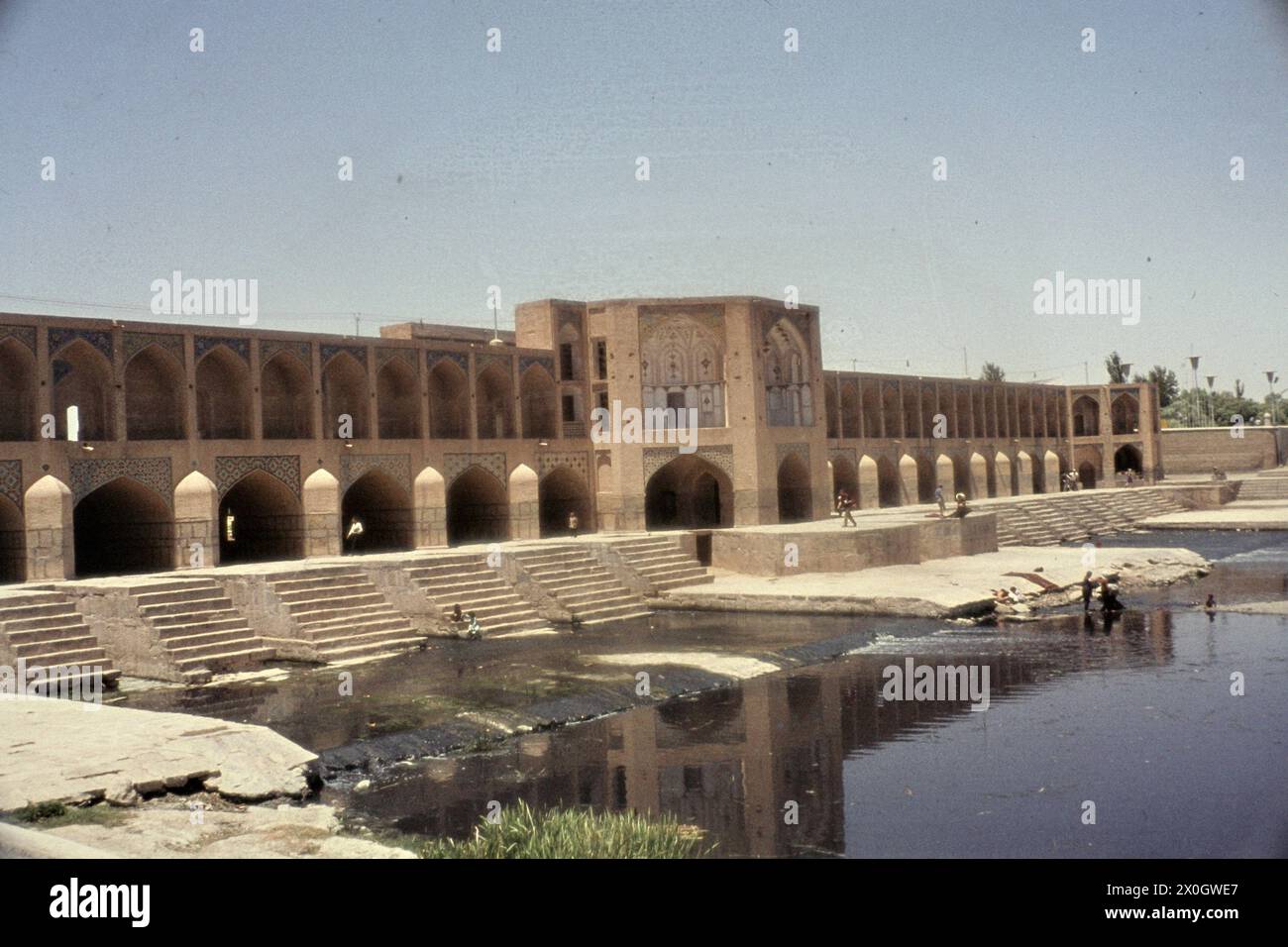 People on the steps of the Kadju Bridge over the Zayanderud River in ...