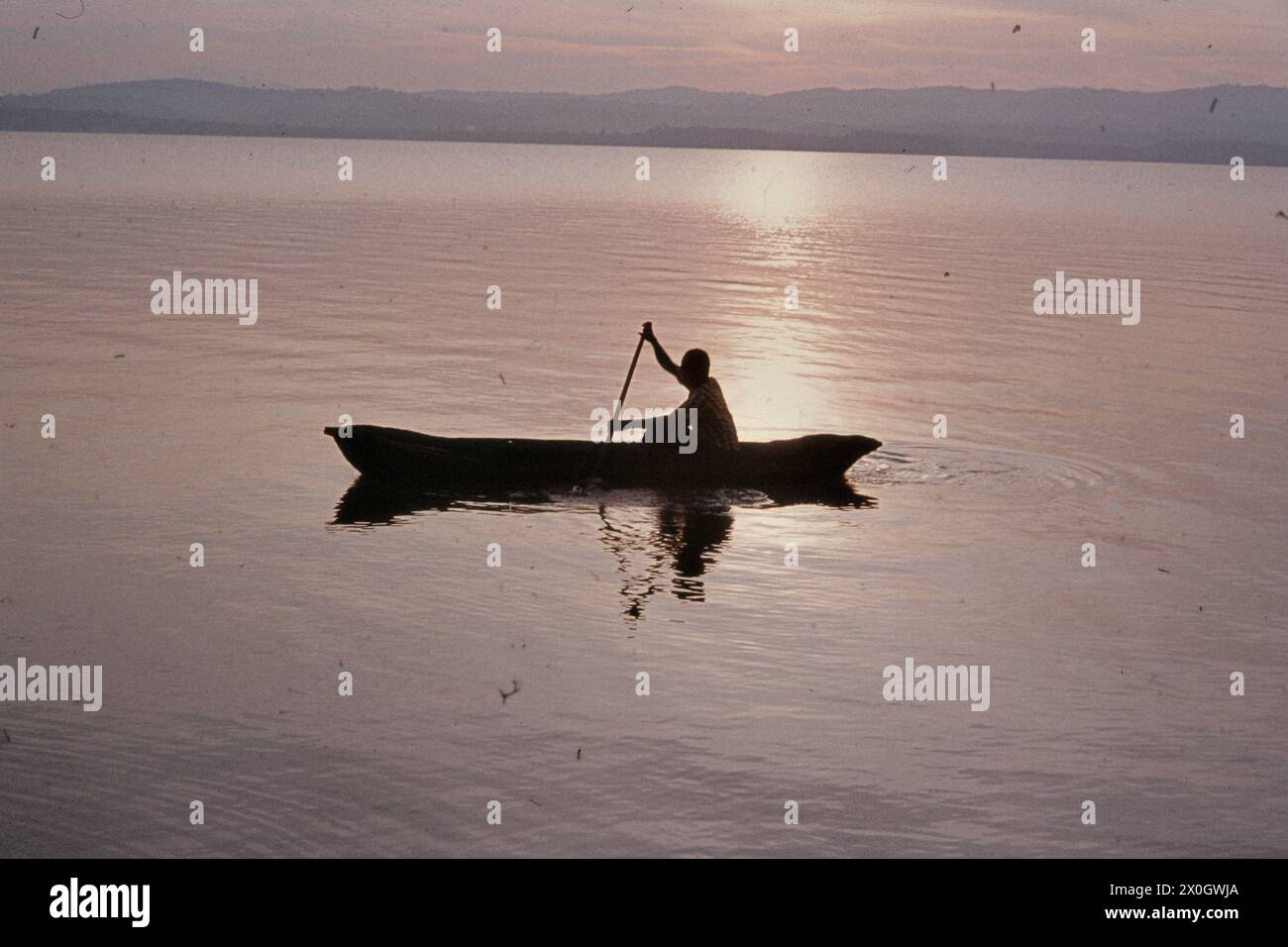 A fisherman in a dugout on Lake Kivu near Bukavu at sunset. [automated ...