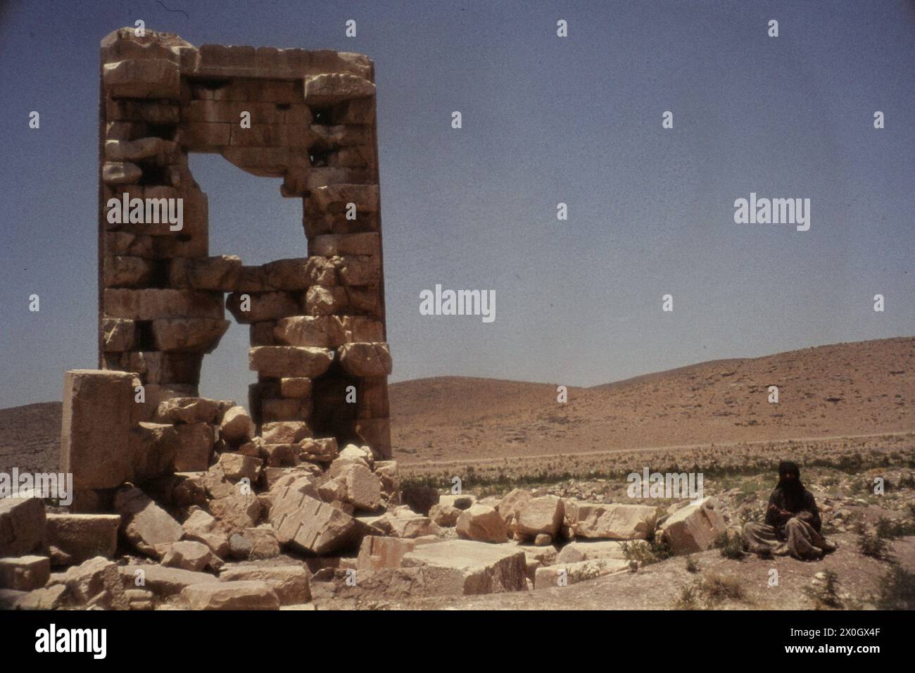 A veiled man is sitting next to the fire temple near the tomb of King ...