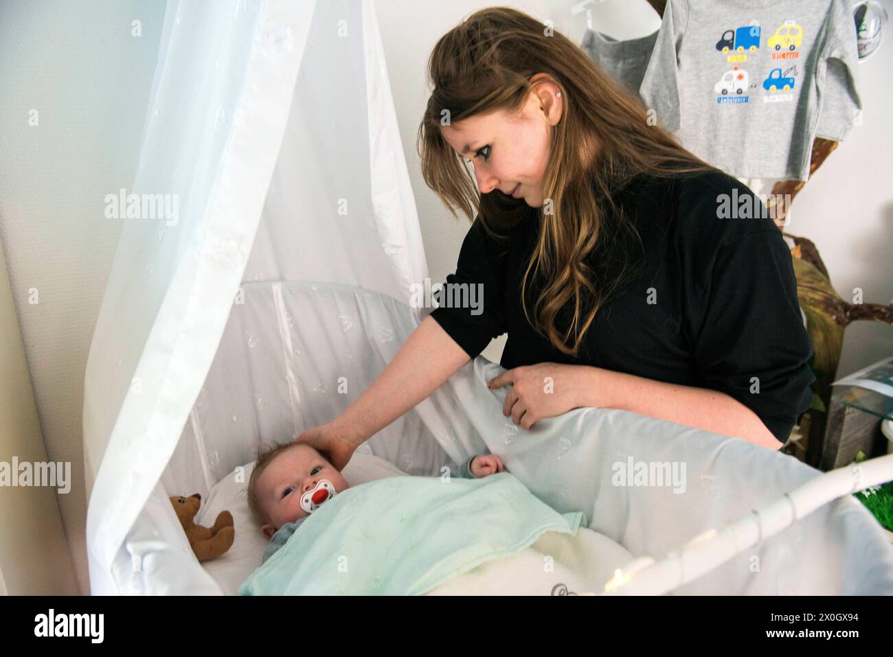 Mother and Child at Cradle Young adult mother putting her baby son to ...