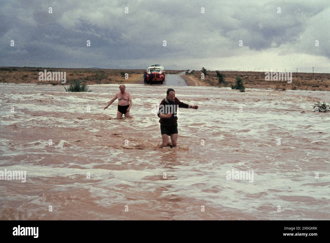 Tourists cross a road flooded by the river Ech-Chaffar in the desert ...