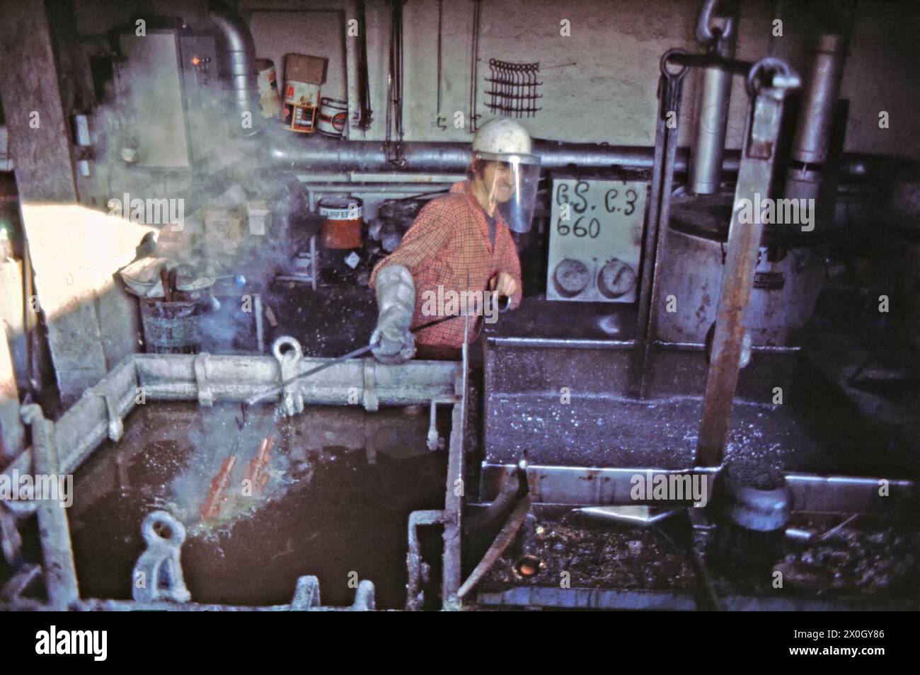 A young man in the wage hardening shop hardening steel and aluminium ...