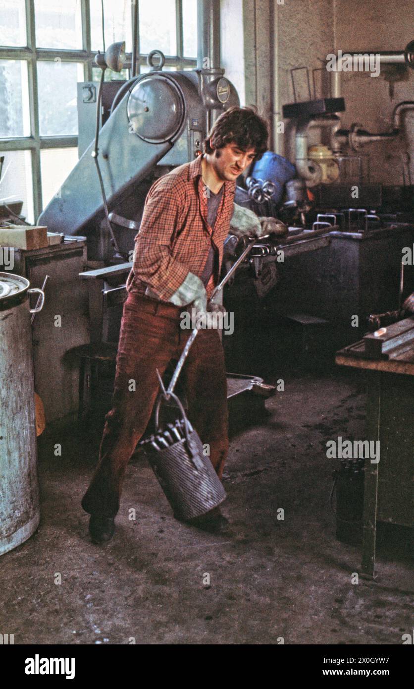 A young man in the wage hardening shop hardening steel and aluminium ...