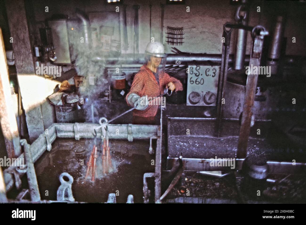 A young man in the wage hardening shop hardening steel and aluminium ...