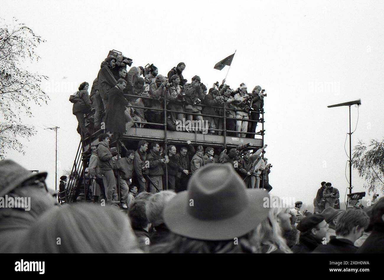 Reporters, photographers and onlookers stand crowded together on a ...