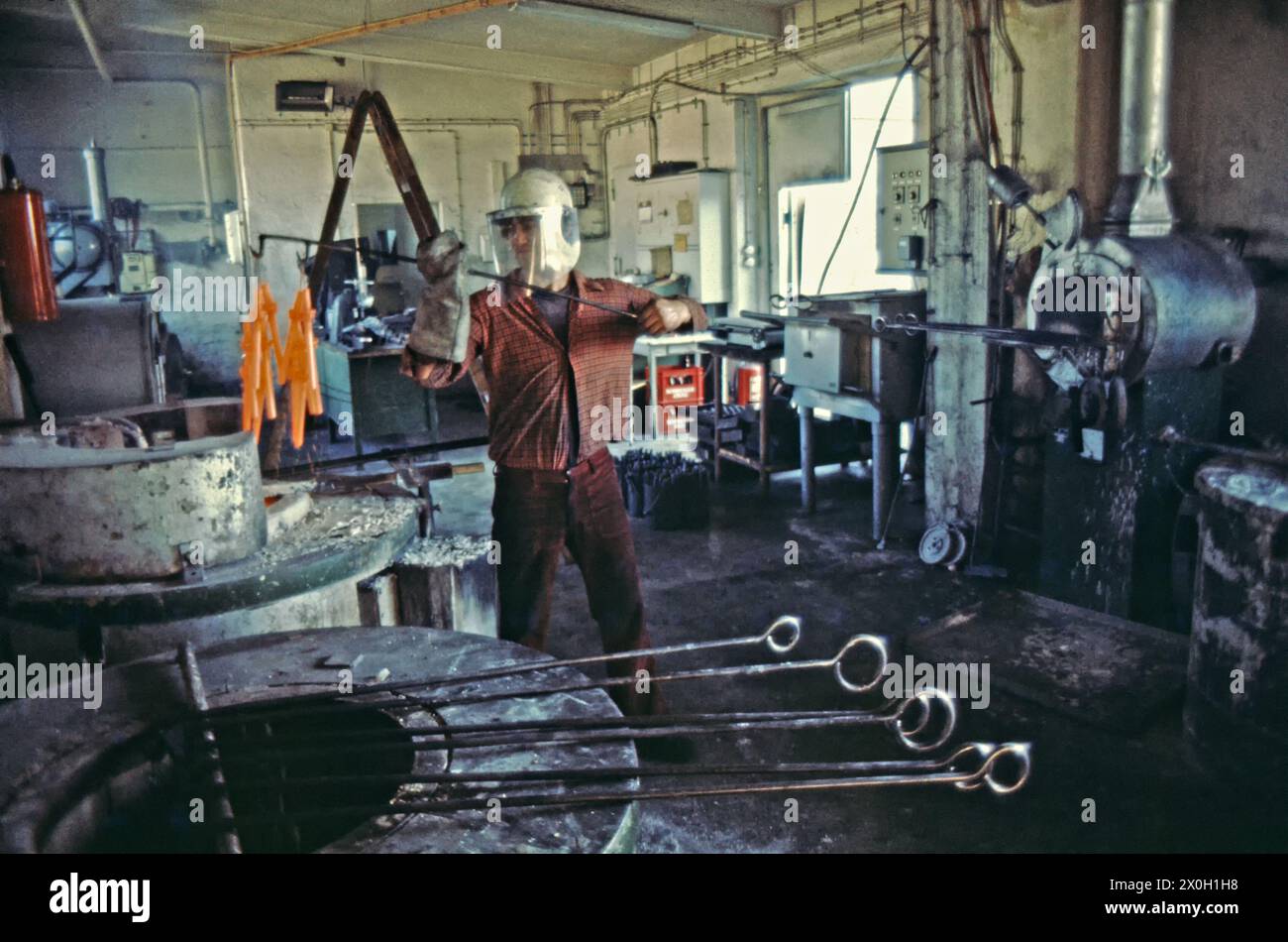 A young man in the wage hardening shop hardening steel and aluminium ...