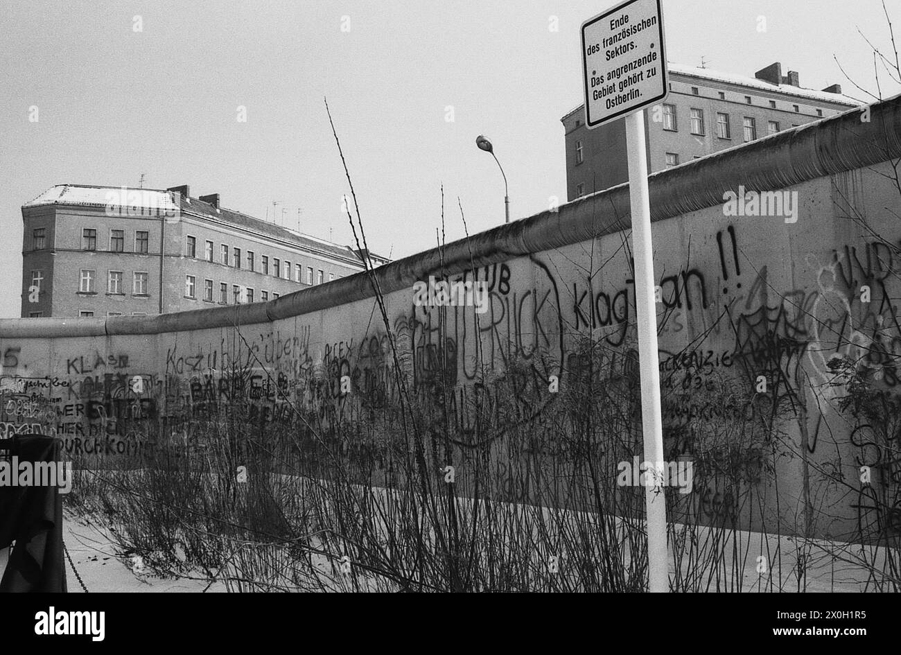 The Berlin Wall in the French sector. On the right is a sign that says ...