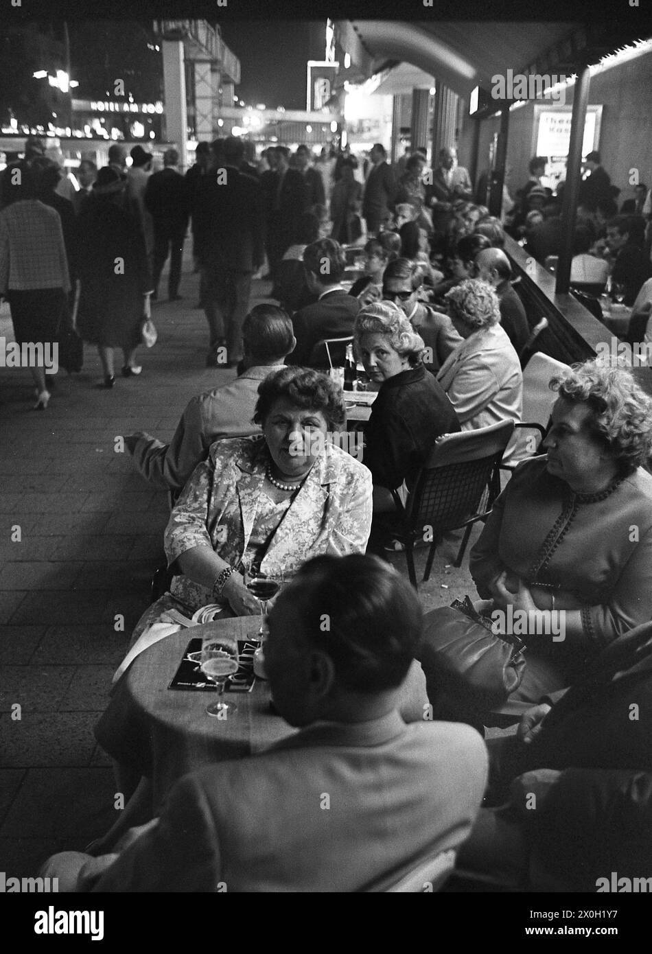 Elderly people sit on the evening at the tables of a cafe on the ...