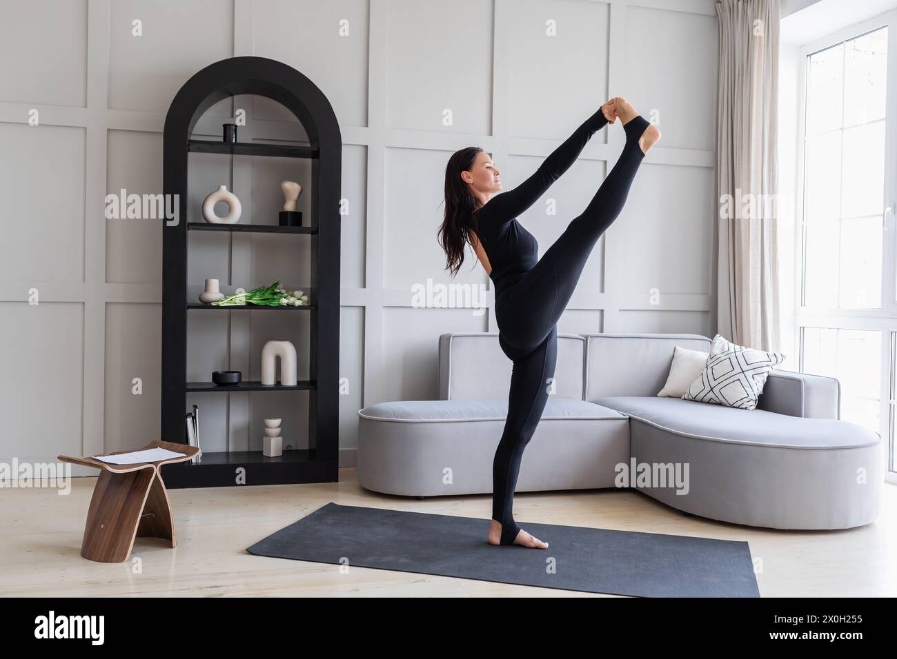 A sporty woman of European appearance trains at home on a mat, performs ...
