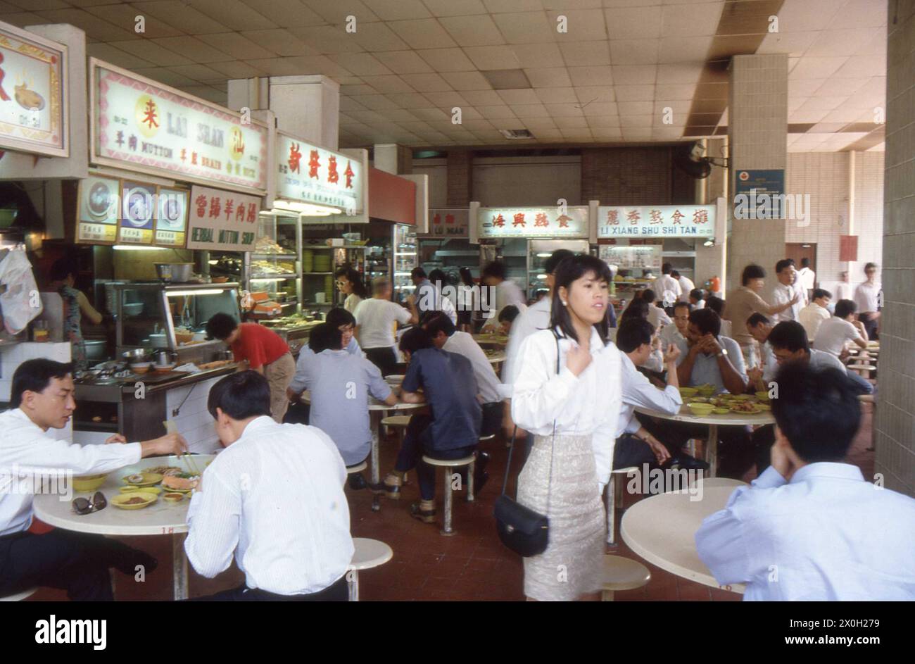 People eating at tables of the food stalls in Singapore (undated ...