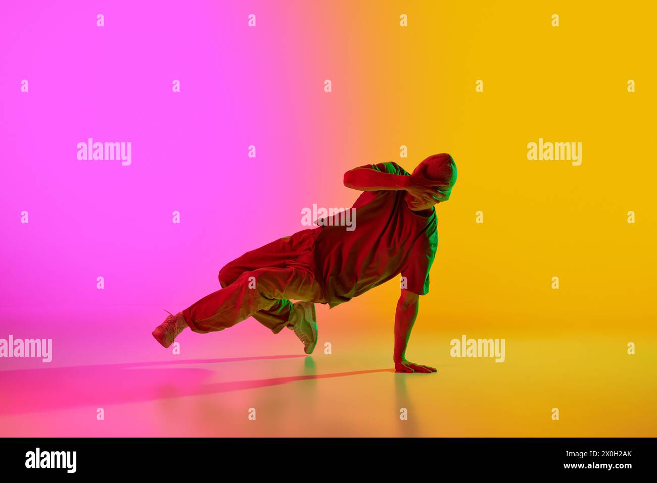 Cool attitude young man performing breakdance in motion in neon light ...