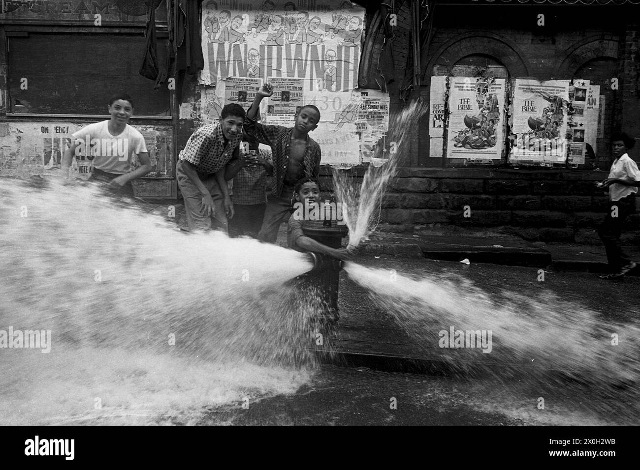 Children play in the heat at a fire hydrant and splash passing cars in ...