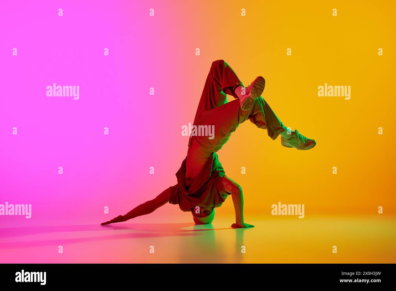 Dynamic photo of break-dancer spinning on head in motion in neon light ...