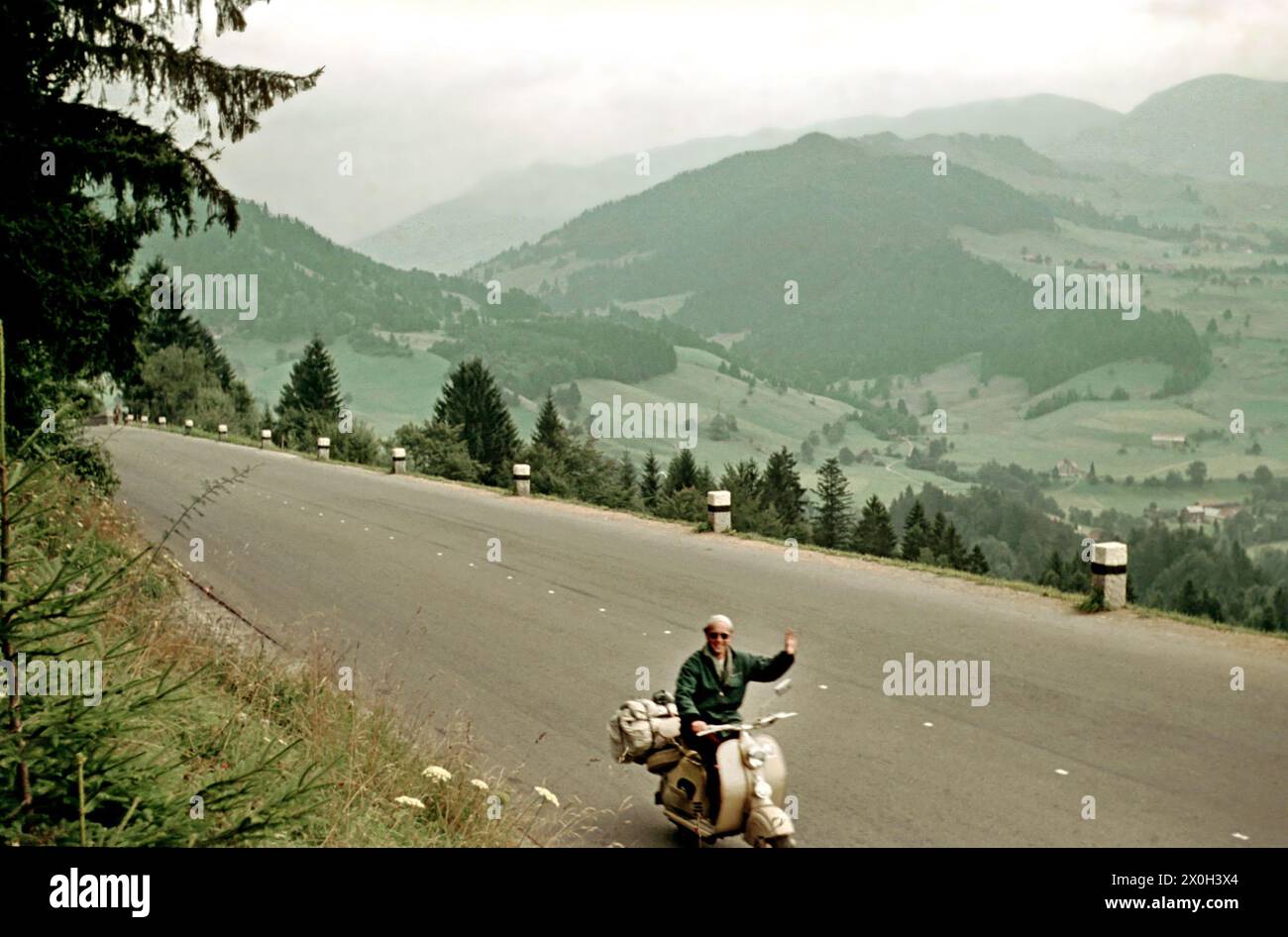A man on his scooter of the brand Lambretta in front of a low mountain ...