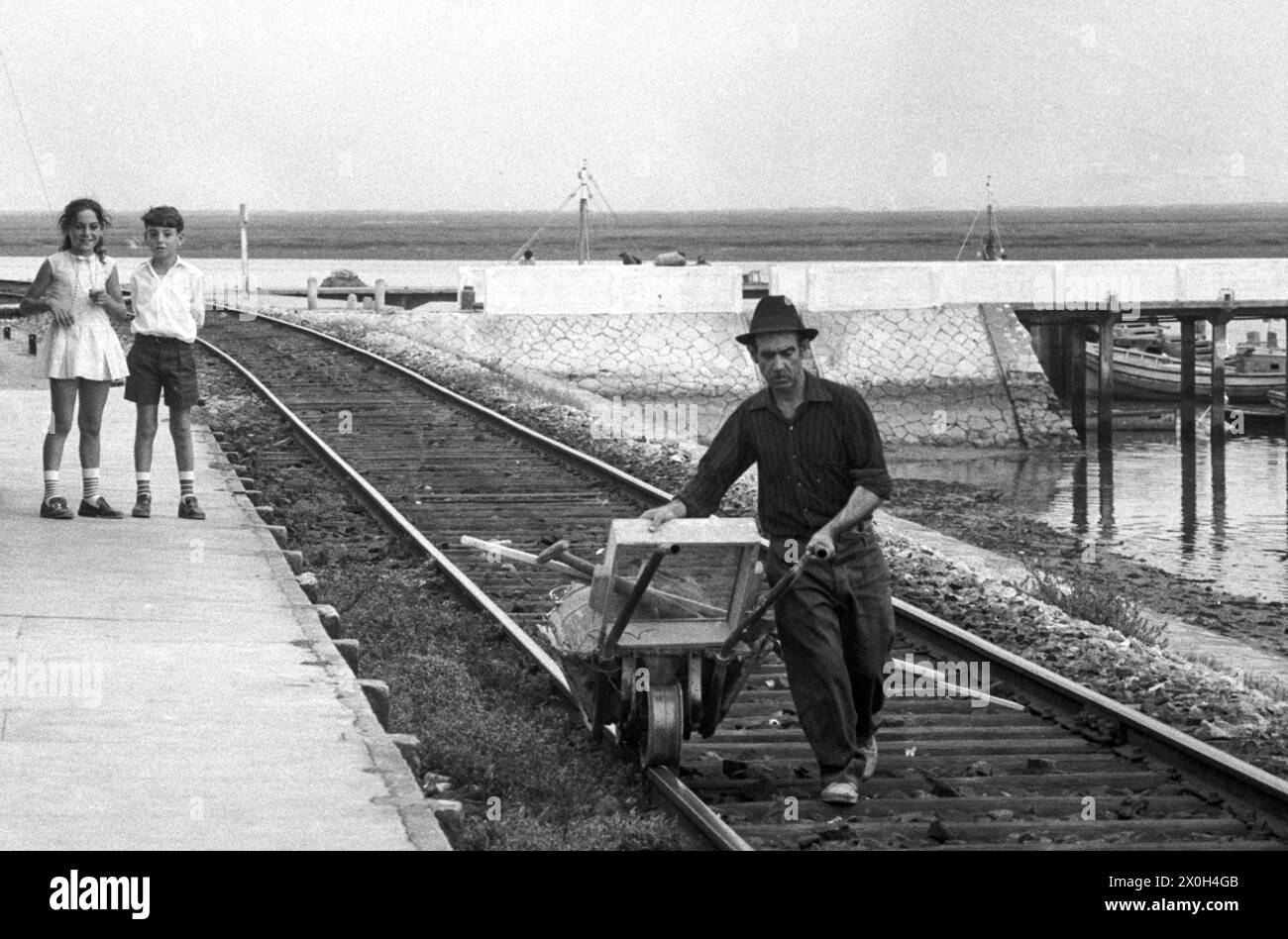 A worker with an unconventional rail wheelbarrow returns from work. Two ...