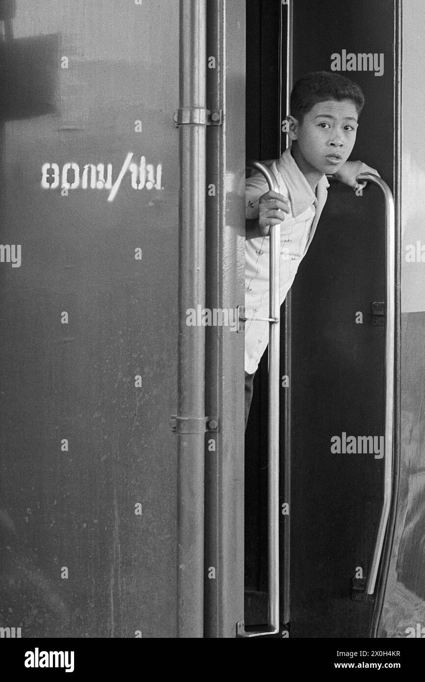At Surat Thani railroad station in Thailand: a boy leans out of the ...