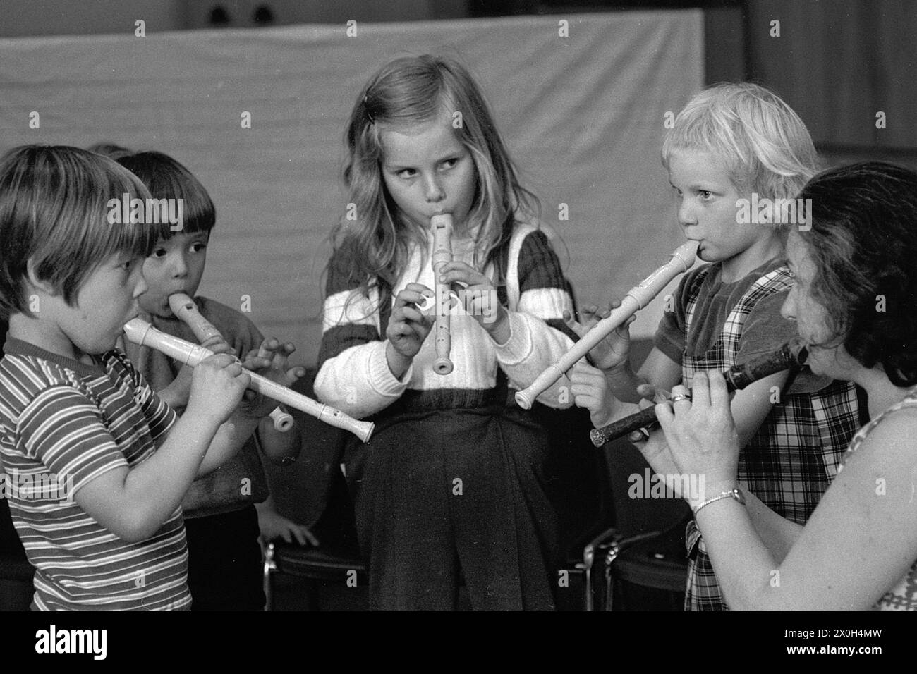 Four children play the trestle flute with the teacher [automated ...