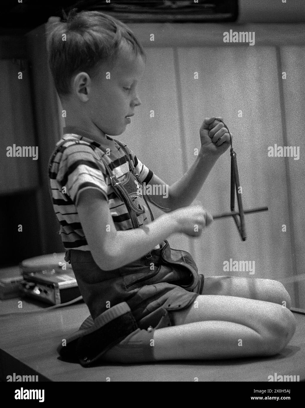 Kneeling on the table, the boy beats the triangle [automated ...