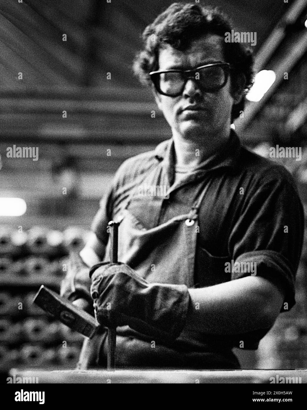 A worker uses a hammer and chisel to remove small production defects ...