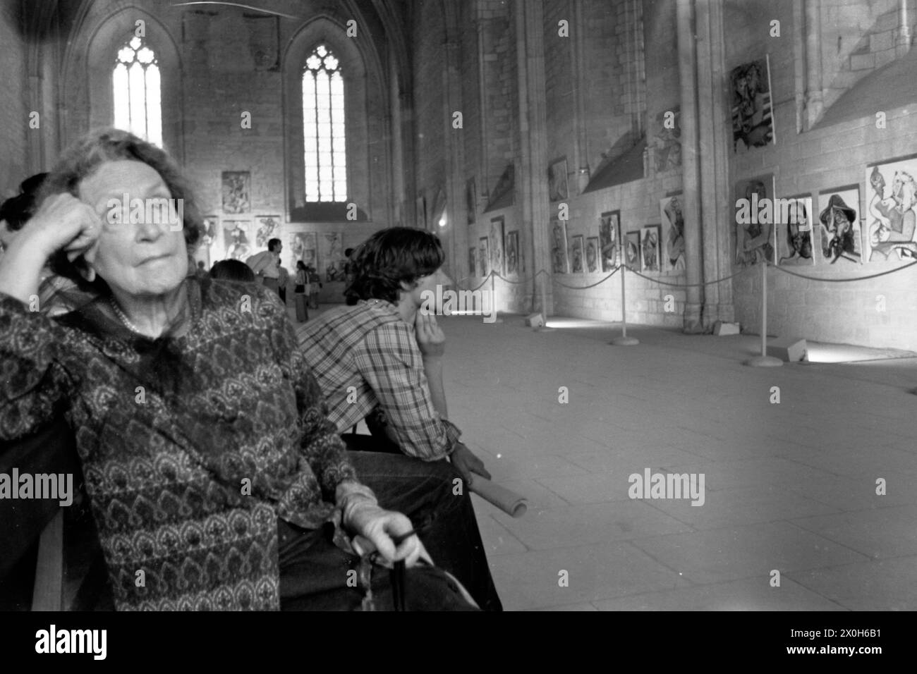 Visitors to a Picasso exhibition in Avignon sit on a long bench. In the ...