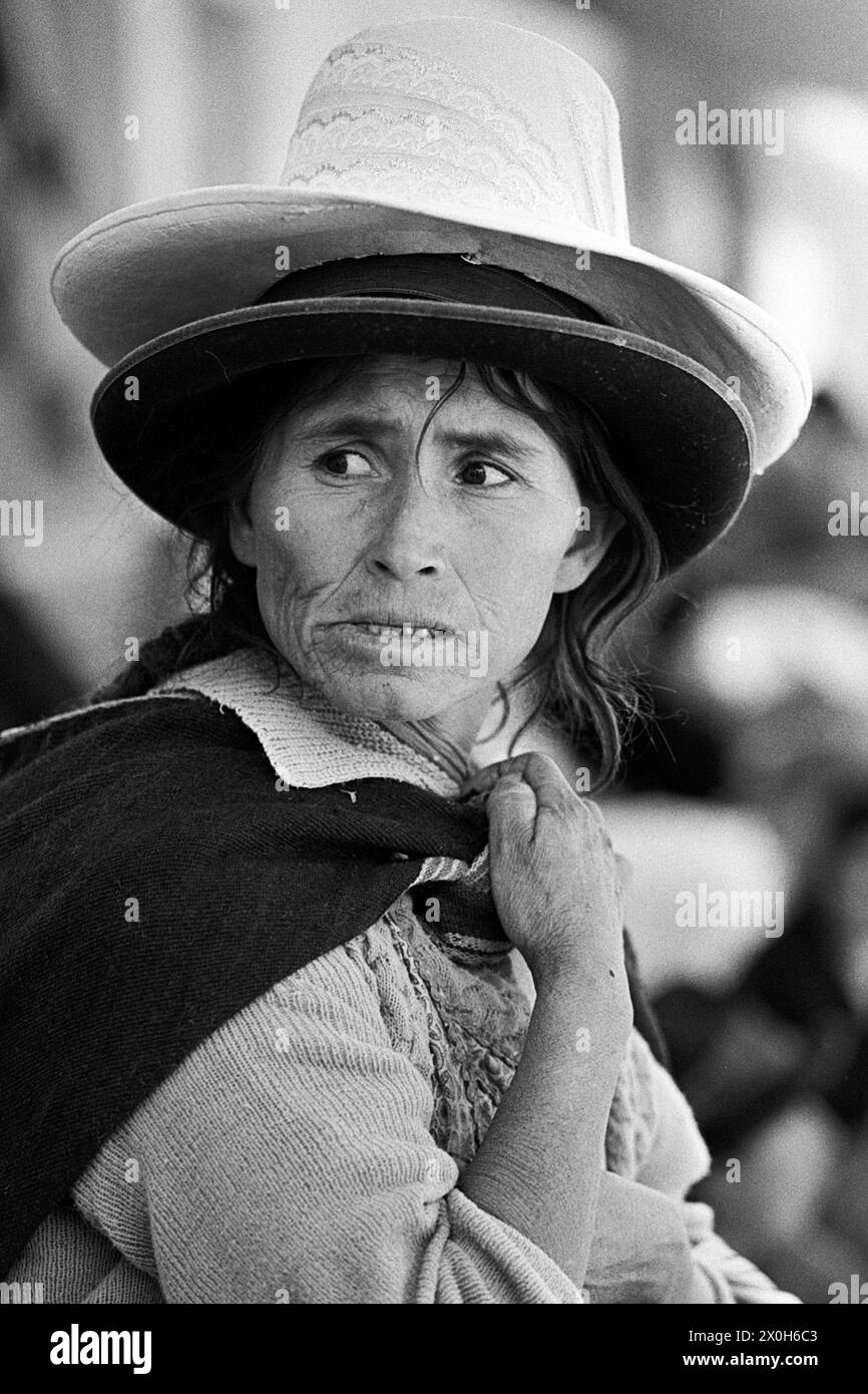 An Indian woman proudly wears two hats on top of each other. Besides ...