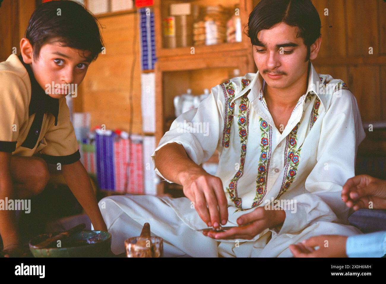 The vendor rolling a packet of betel nuts is also dressed festively ...