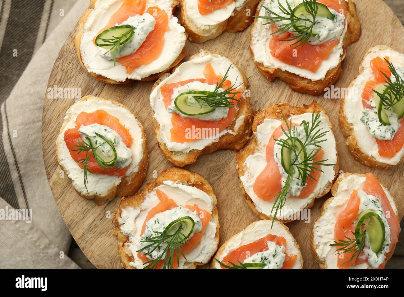 Tasty canapes with salmon, cucumber, cream cheese and dill on table ...