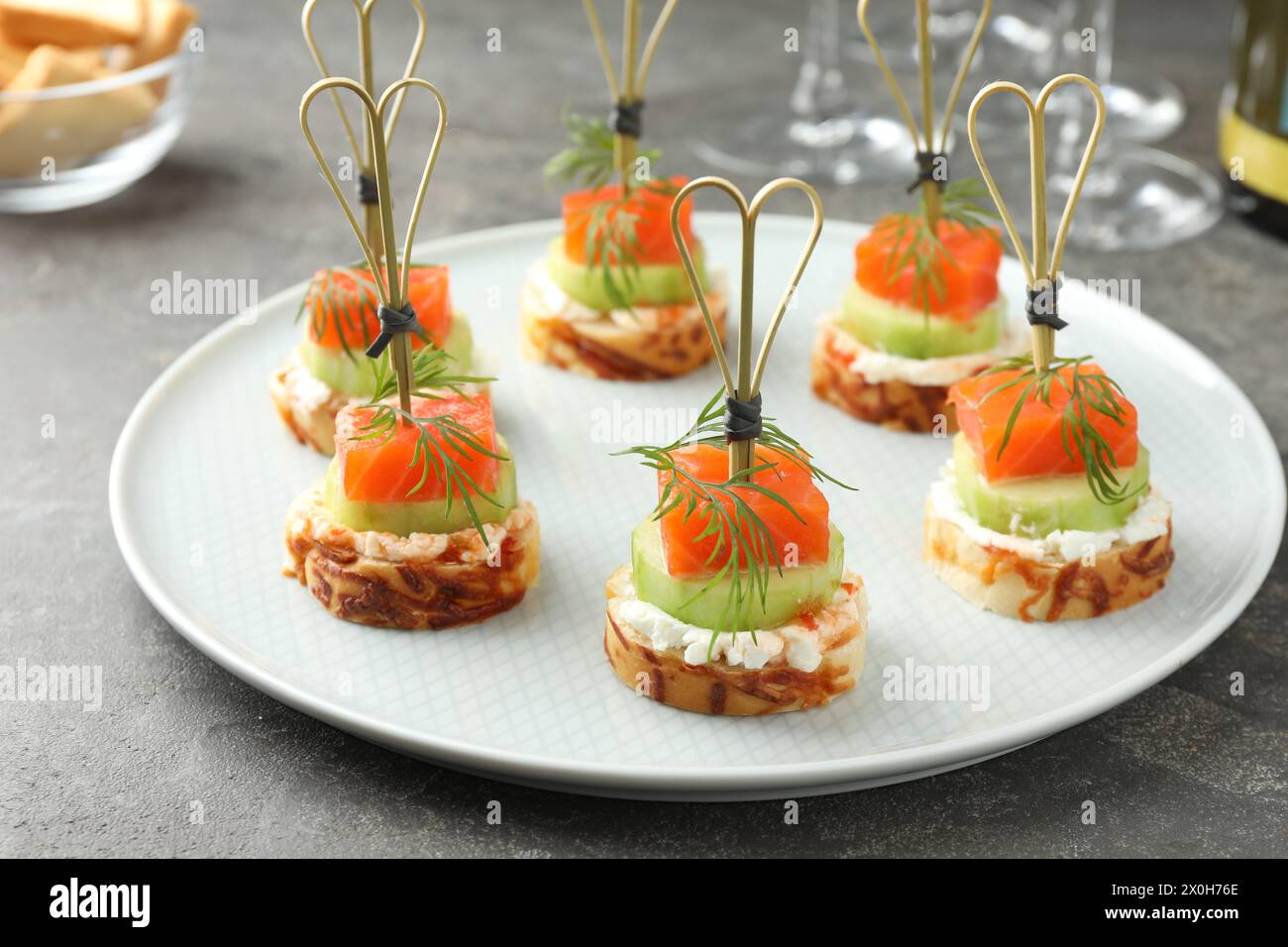 Tasty canapes with salmon, cucumber, bread and cream cheese on grey ...