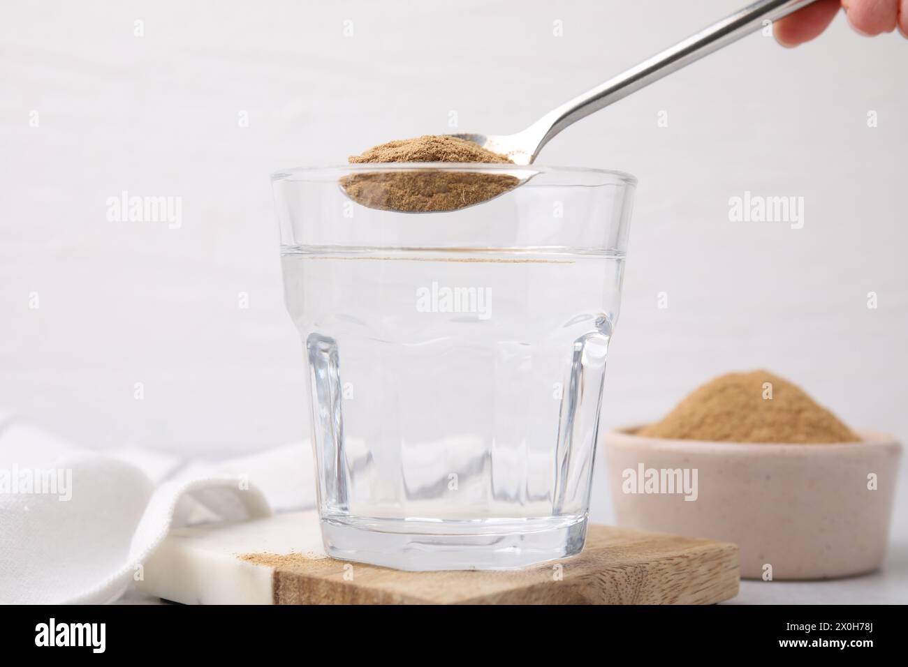 Dietary fiber. Woman adding psyllium husk powder into water at table ...
