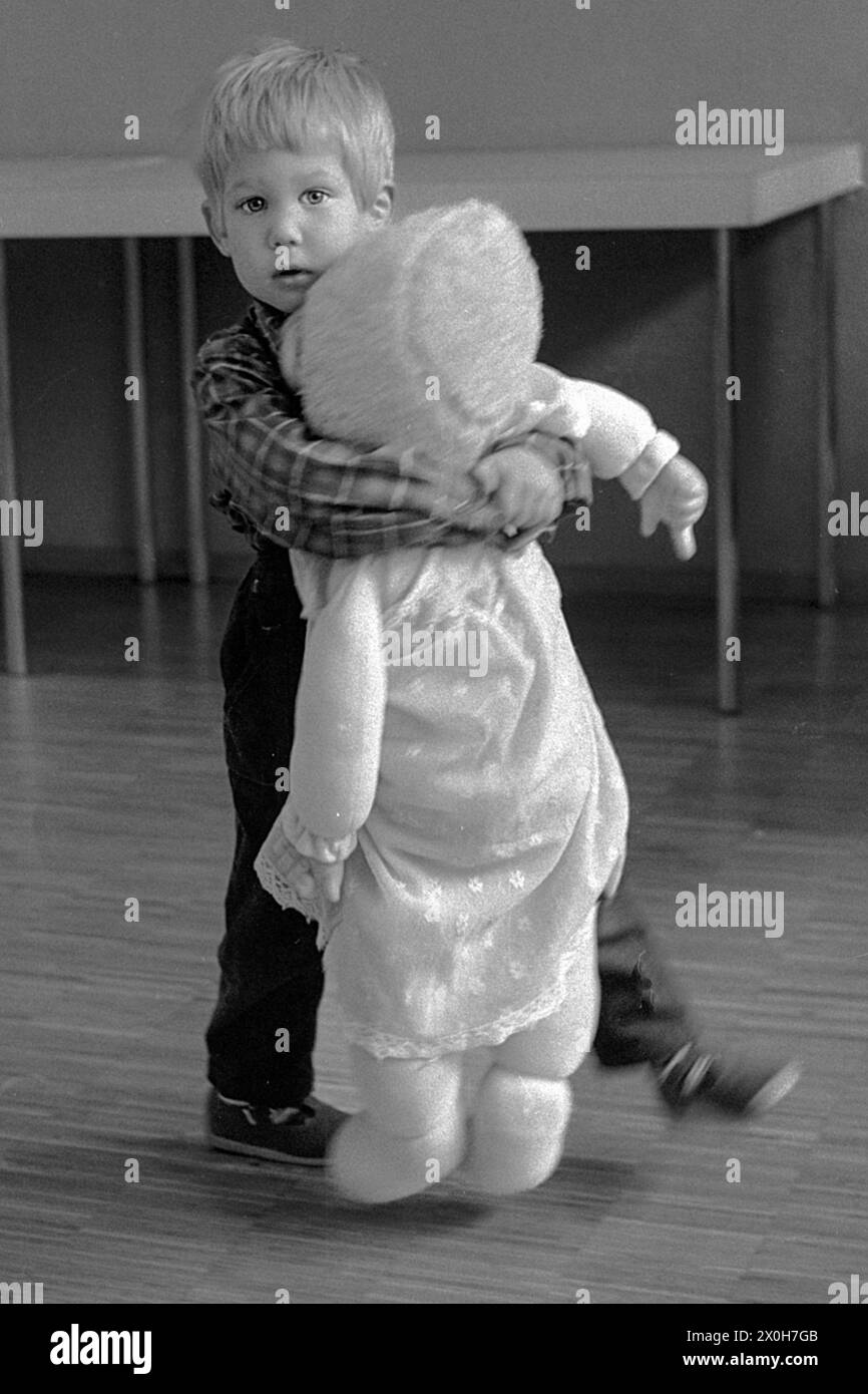 The boy carries the life-size rag doll around with a long stride ...