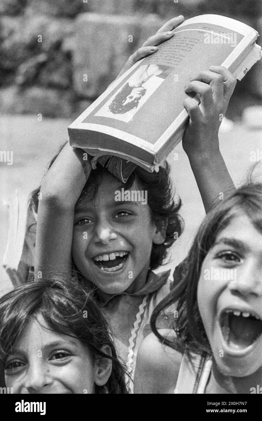 Three smiling girls from Aleppo. They proudly raise their schoolbooks ...