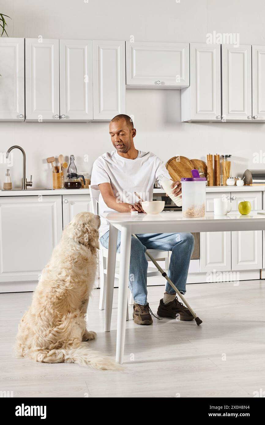 A disabled African American man sits at a kitchen table with his loyal ...