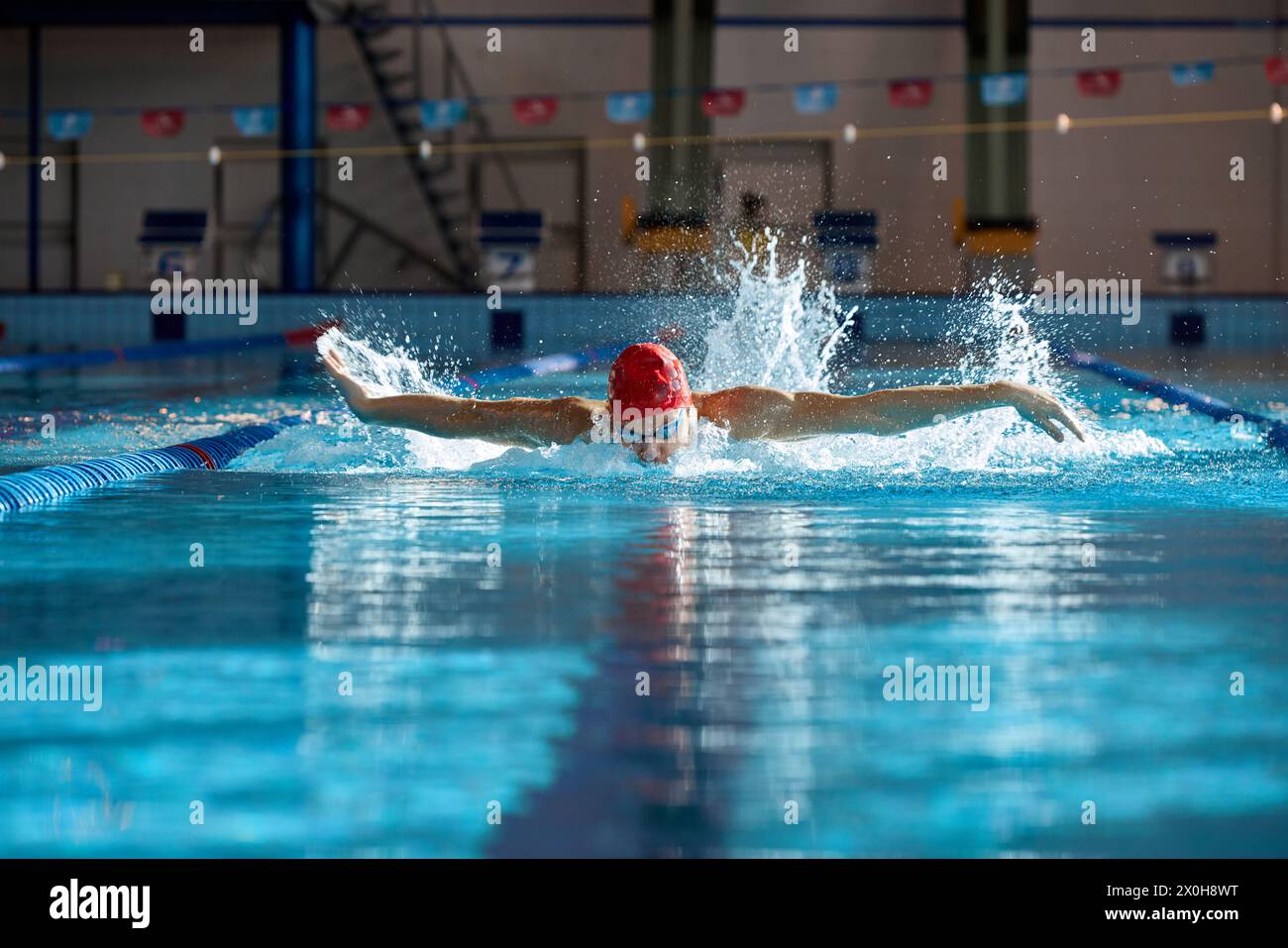 Competitive swimmer in red cap and goggles in motion, training ...