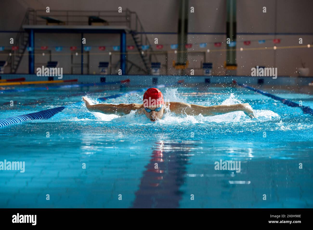 Competitive swimmer in red cap and goggles in motion, training ...