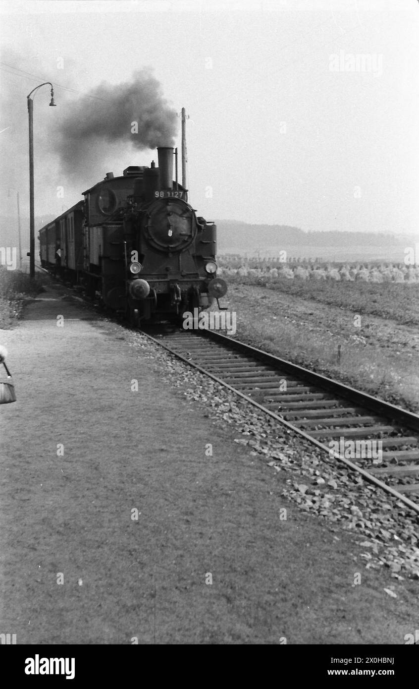 A slow train pulled by a class 98 1127 steam locomotive pulls into a ...