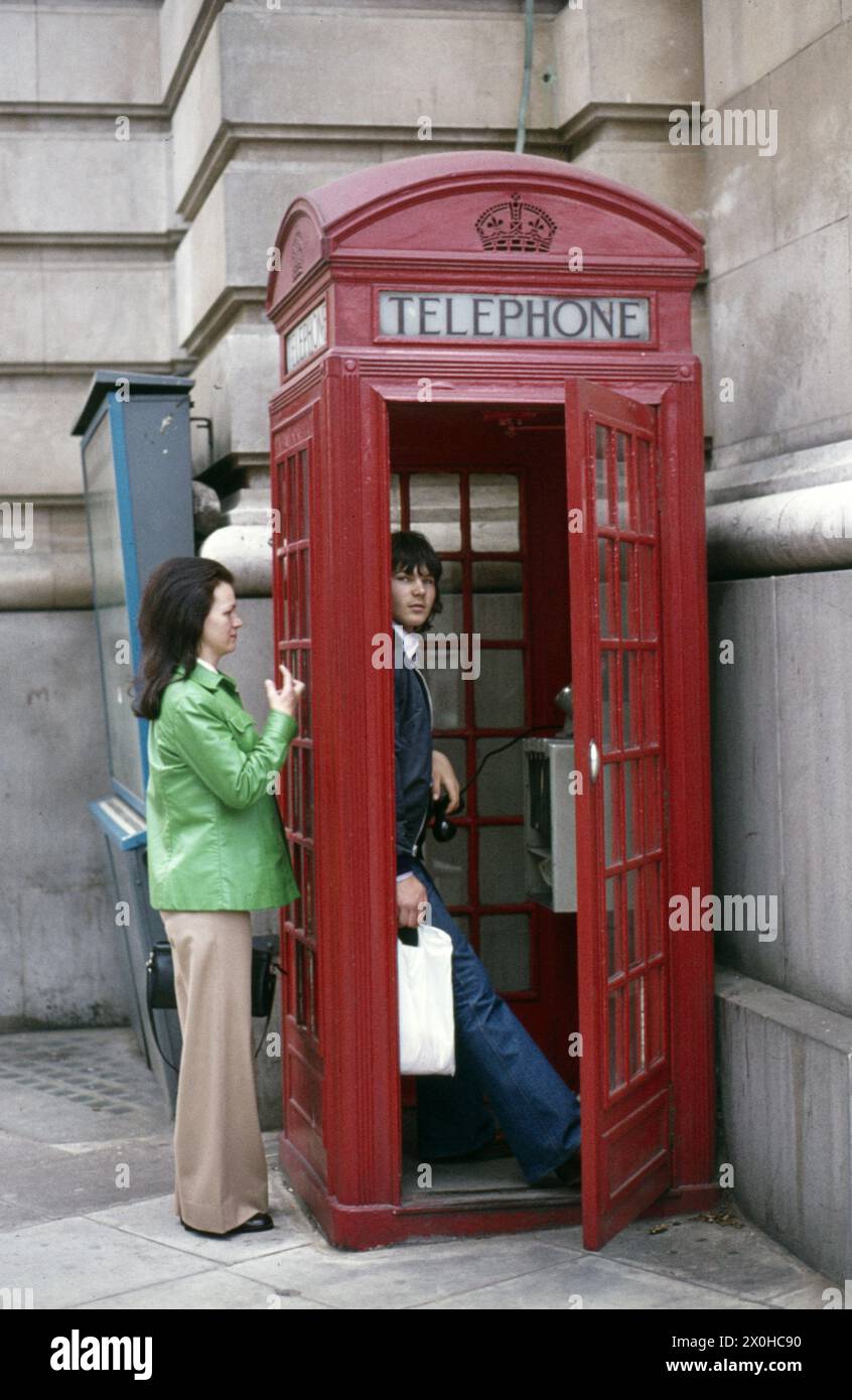 View of a telephone box in London. A man is standing in the phone booth ...