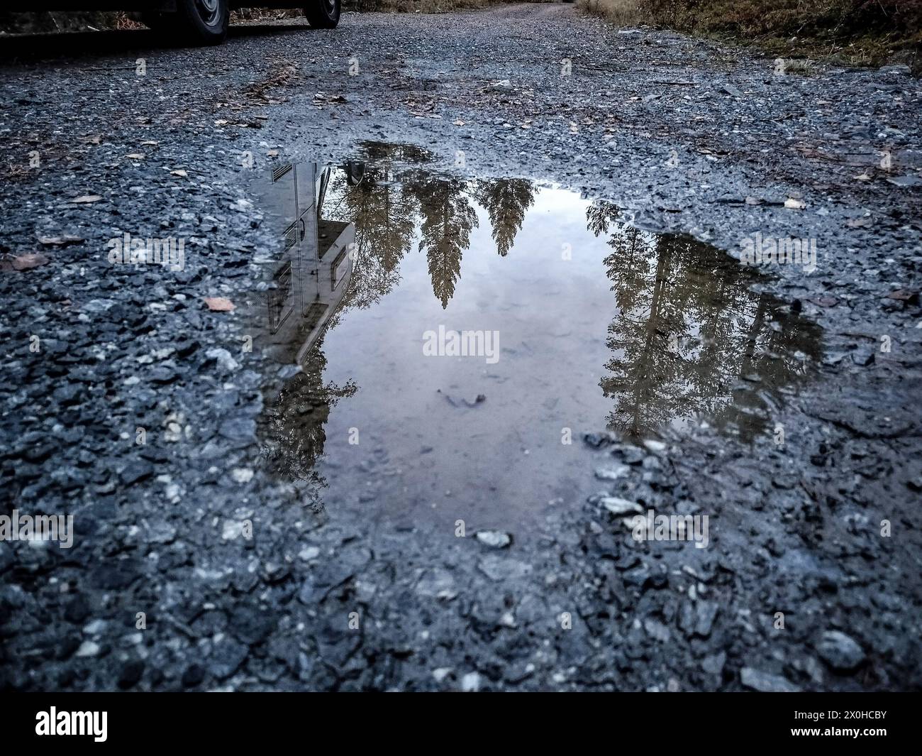 Trees and motorhome reflected in puddle on gravel path Stock Photo - Alamy