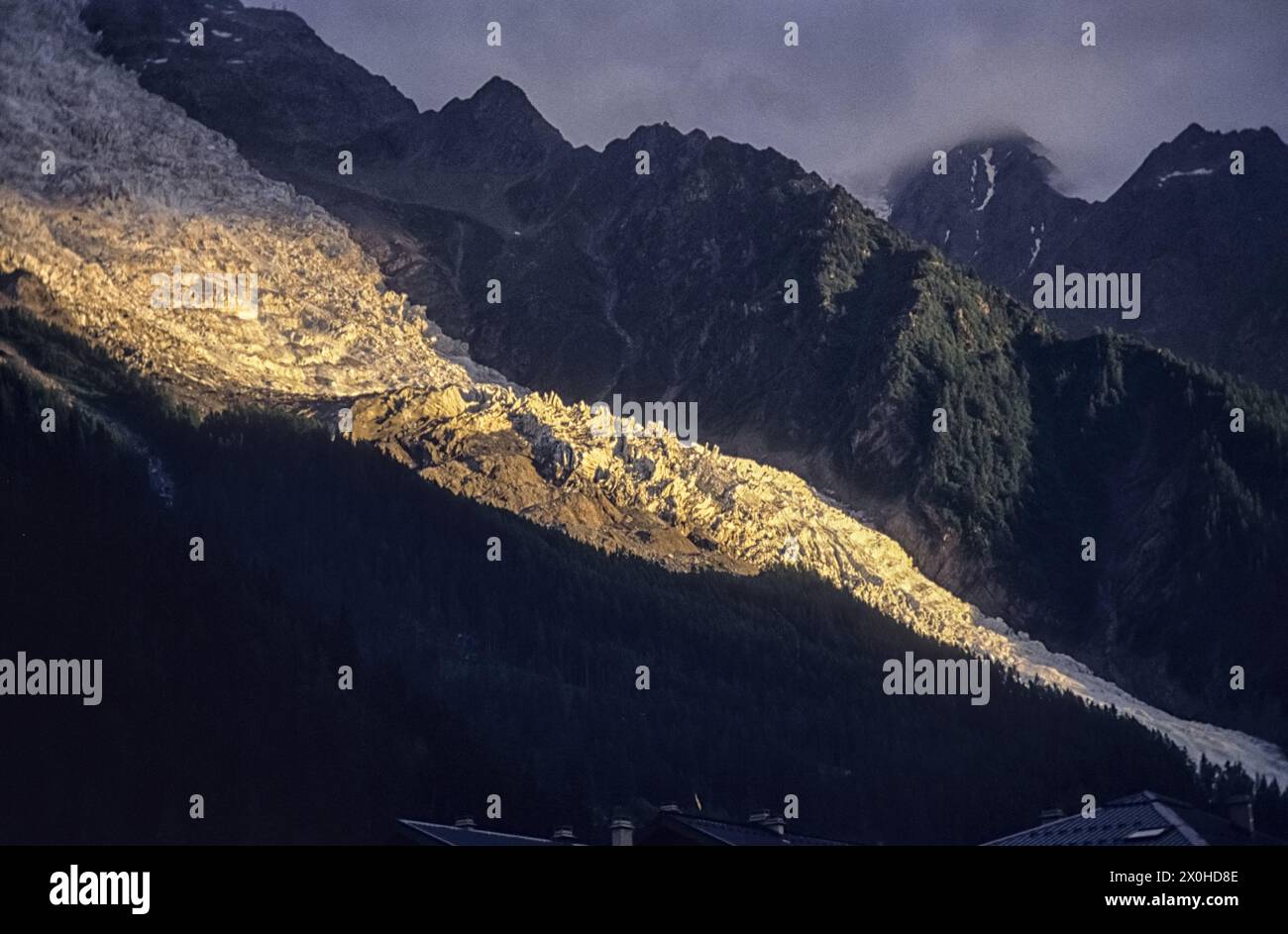The Bossons glacier in the evening sun. Parts of the roofs of the ...