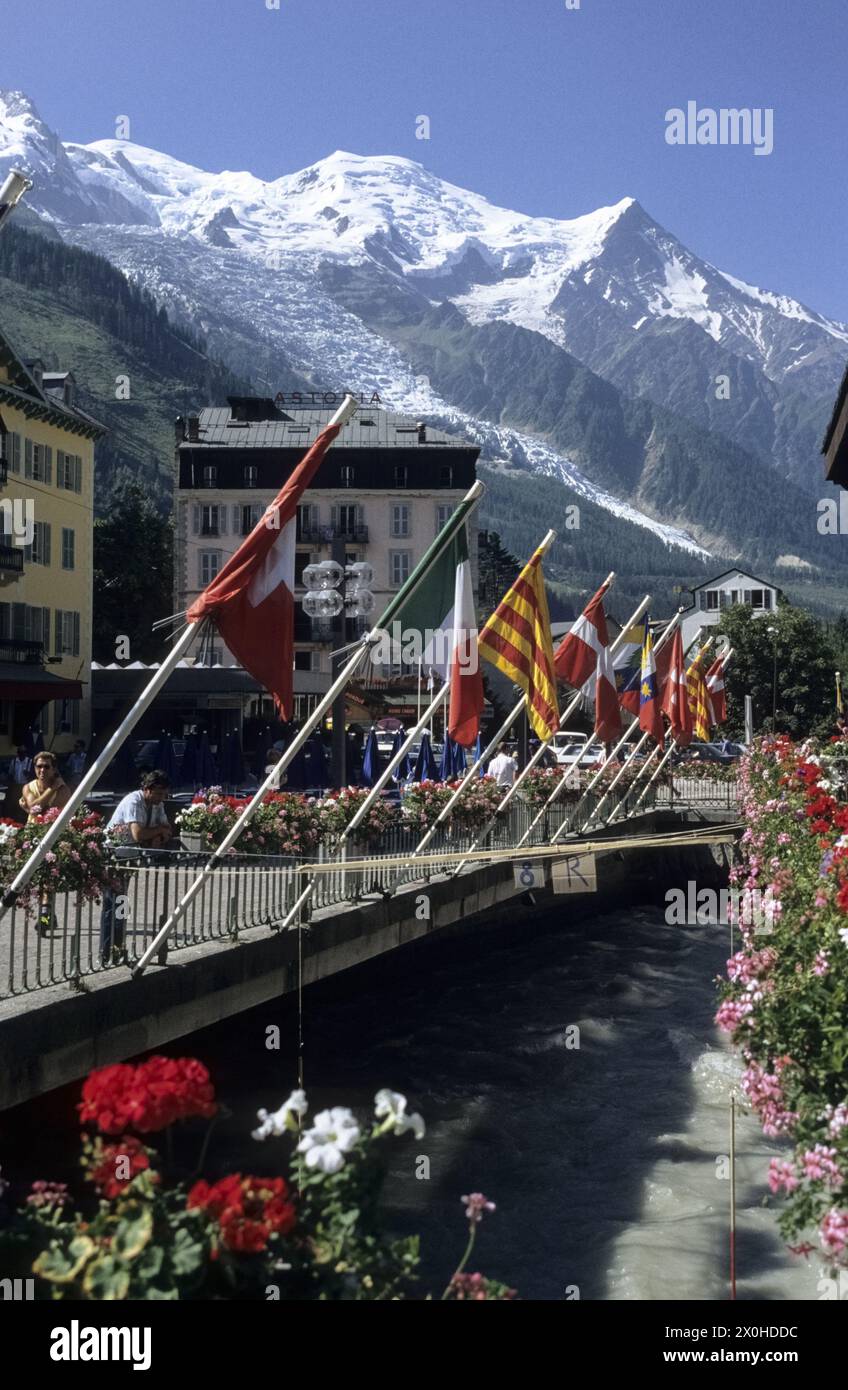 Colorful flags and boxes with geraniums are attached to the railing of ...