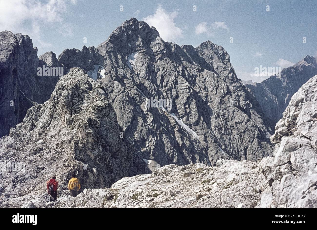Two hikers descend from the hut via the Südscharte. View of ...