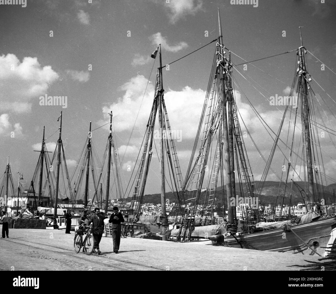 Passersby and sailing boats at the port of Morocco around 1960 Stock ...