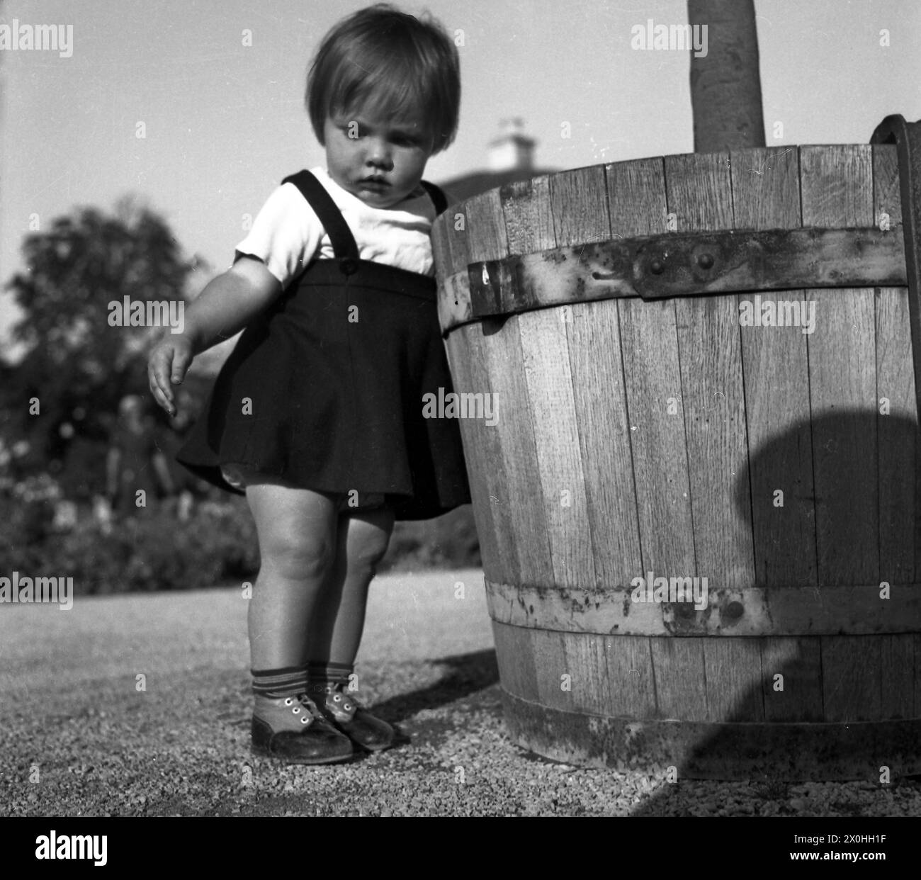 A little girl standing next to a wooden bucket Stock Photo - Alamy