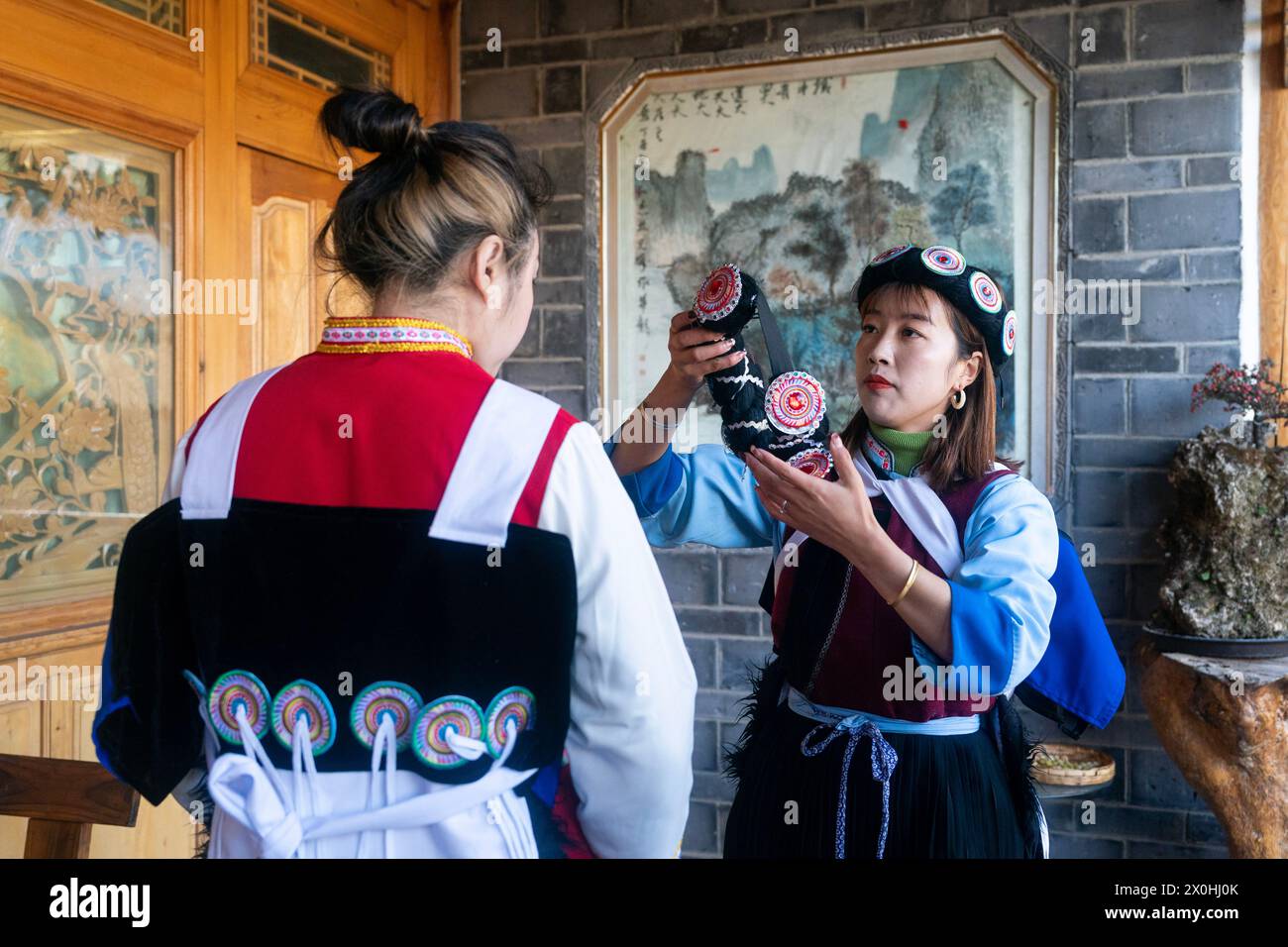(240412) -- LIJIANG, April 12, 2024 (Xinhua) -- He Yuyue (R) helps a ...