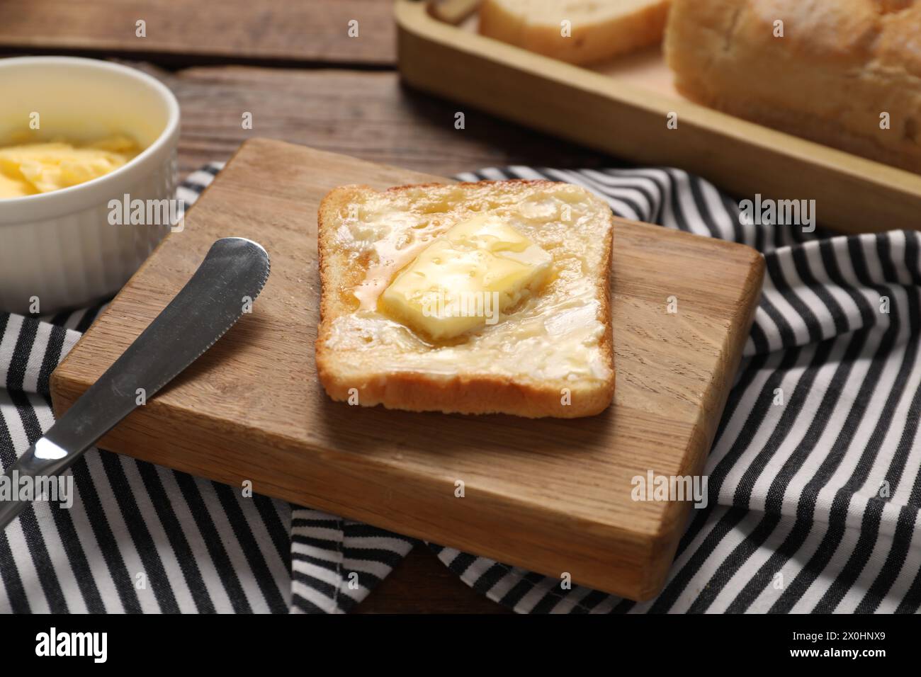Melting butter, toast and knife on wooden table, closeup Stock Photo ...