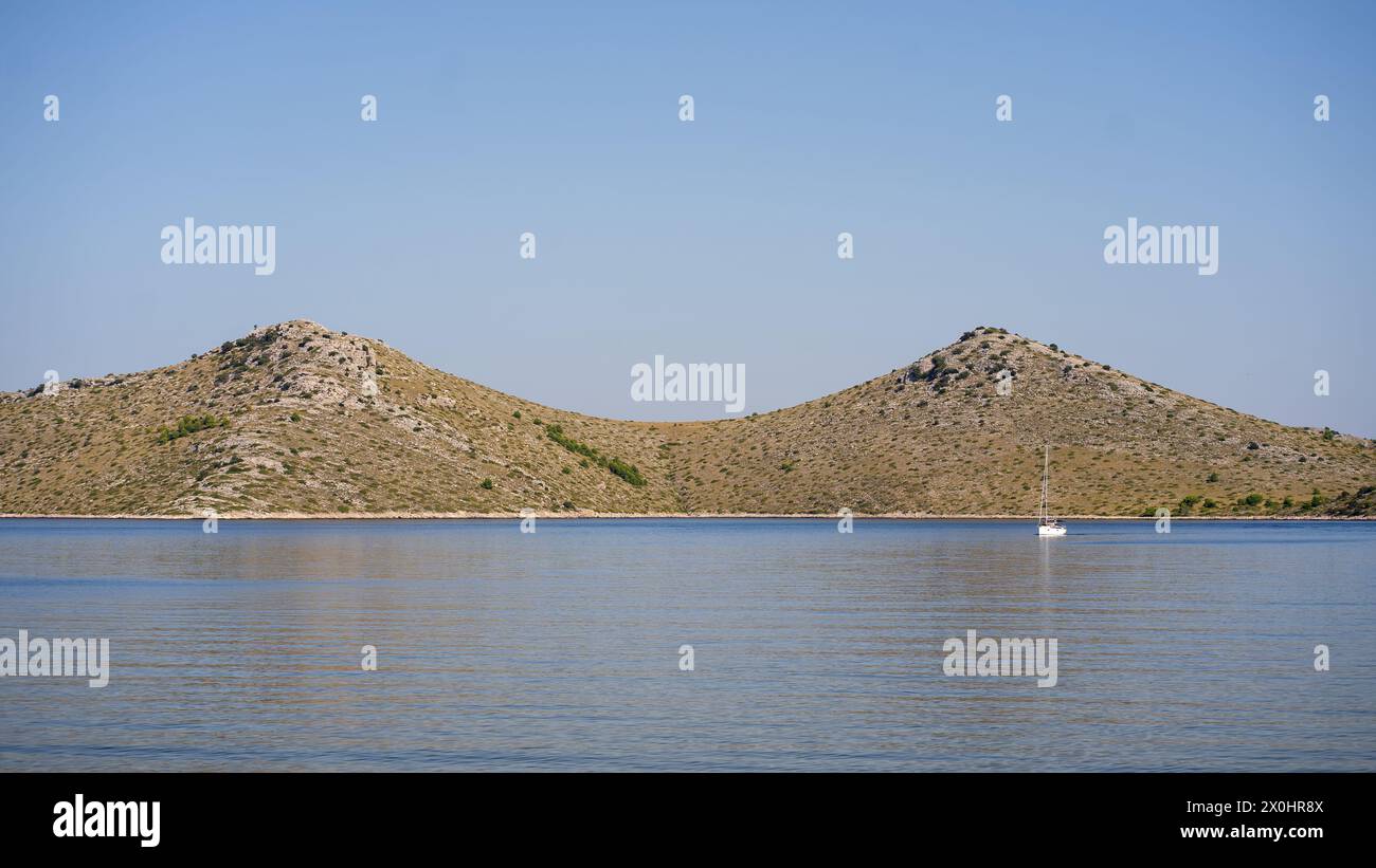 Yacht sailing on calm Adriatic Sea waters near coast with endless hills ...