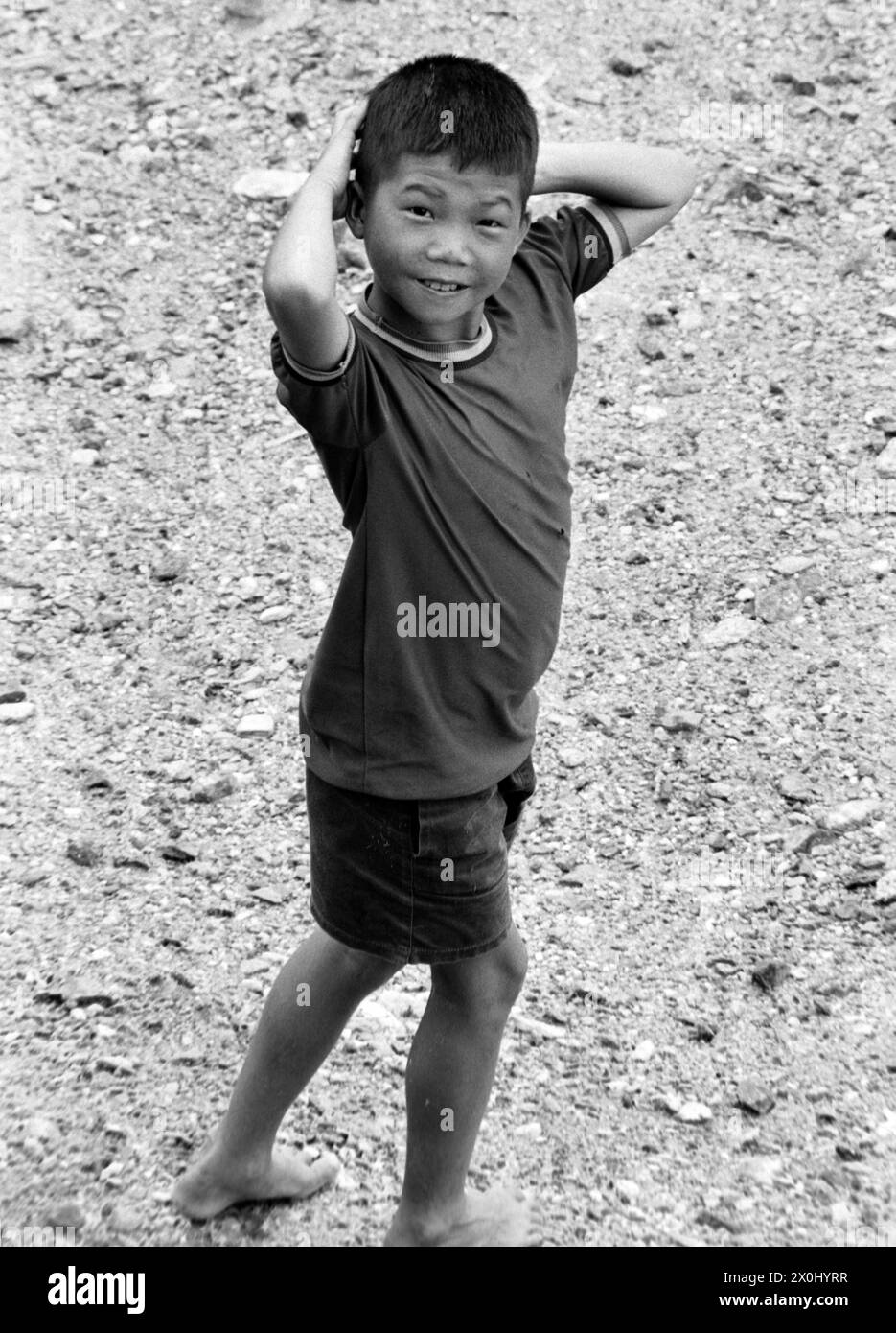 A boy poses for a photo in Hong Kong. He's standing on a rocky square ...