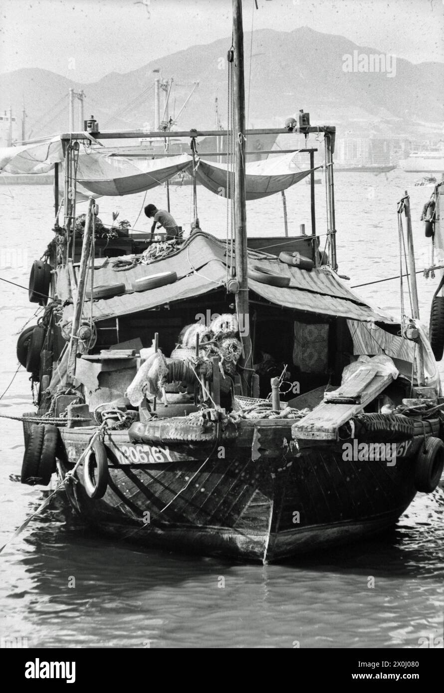 A sampan lies in the port of Hong Kong. It is moored to the left and ...